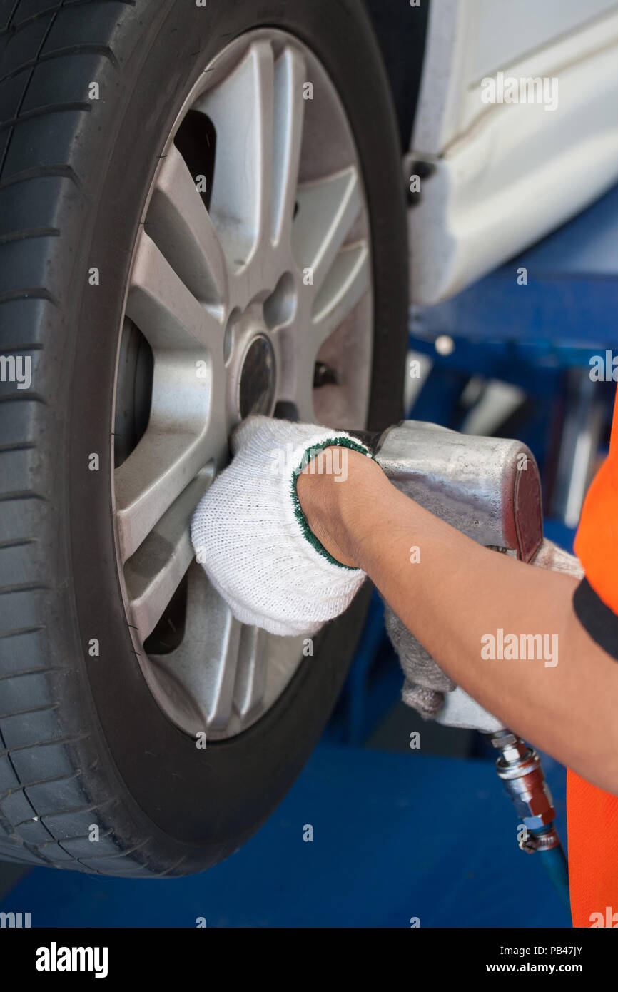 car mechanic screwing or unscrewing car wheel of lifted automobile by ...