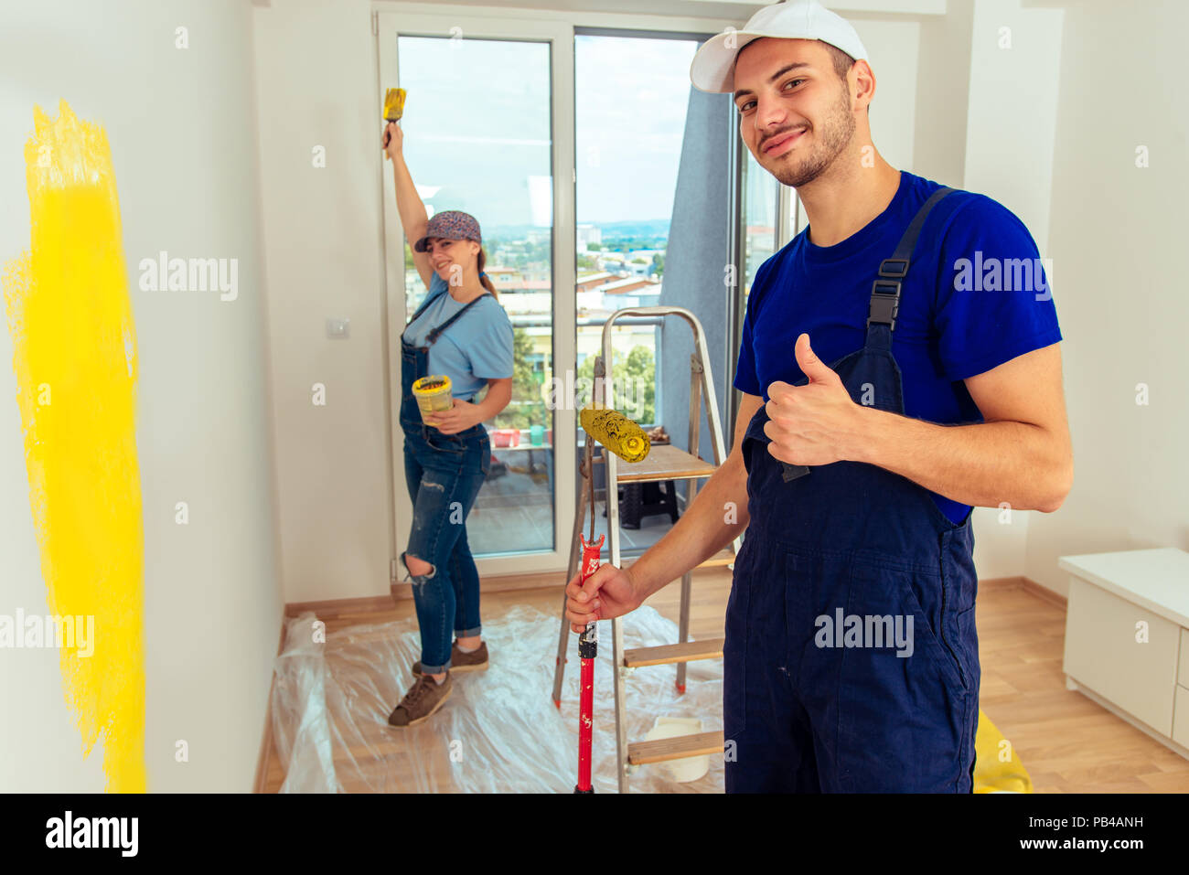 Side view of woman painting wall in yellow by paintbrush Stock Photo ...
