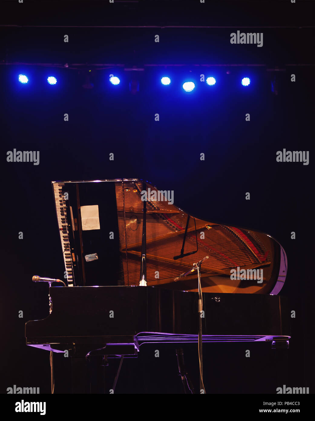Closeup view of big stage concert piano, opened and miked, ready for ...