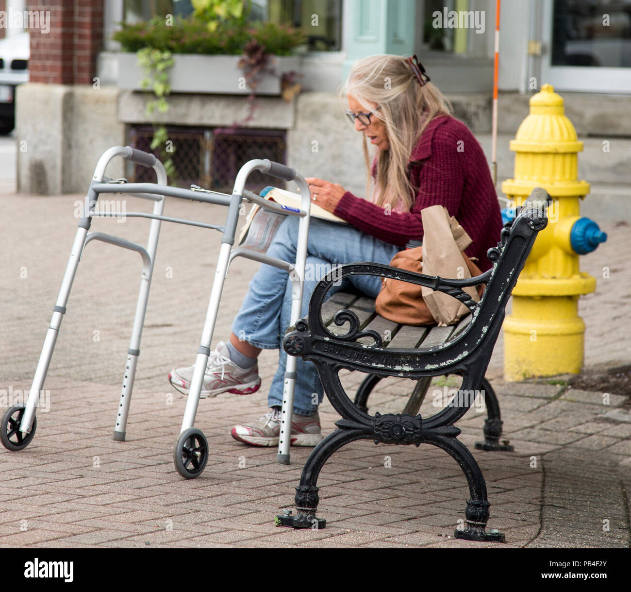 Older women sitting on a bench with her walker by her side Stock Photo ...