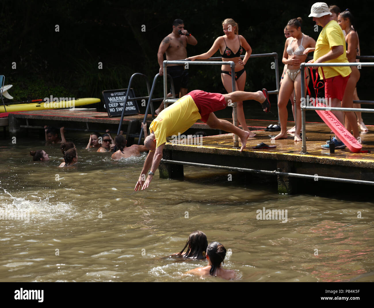 A man dives into the mixed bathing pond on Hampstead Heath, London, as ...