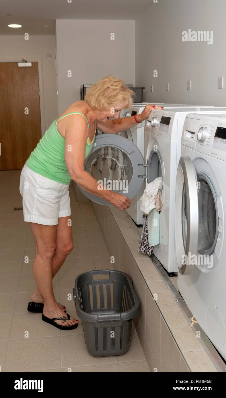 Woman using a washing machine in a laundry room Stock Photo - Alamy