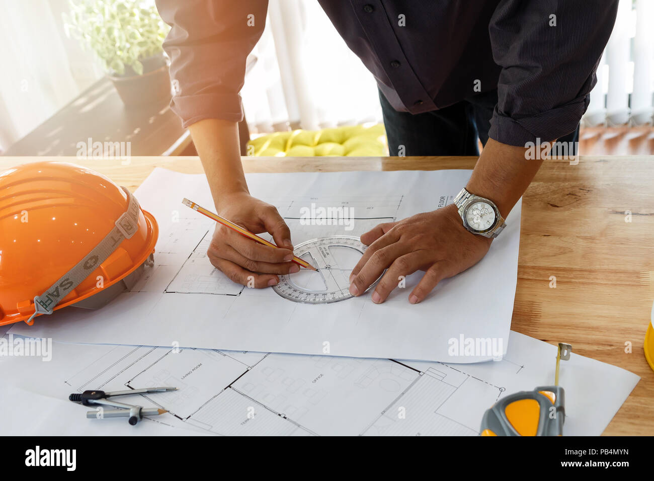 Architect or engineer using pencil and protractor working on blueprint ...