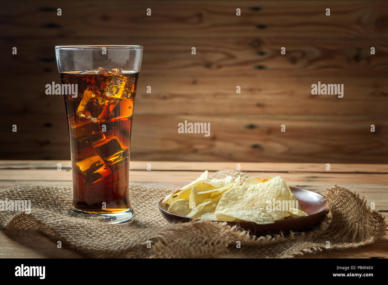 Potato chips with cola on a wooden background Stock Photo - Alamy