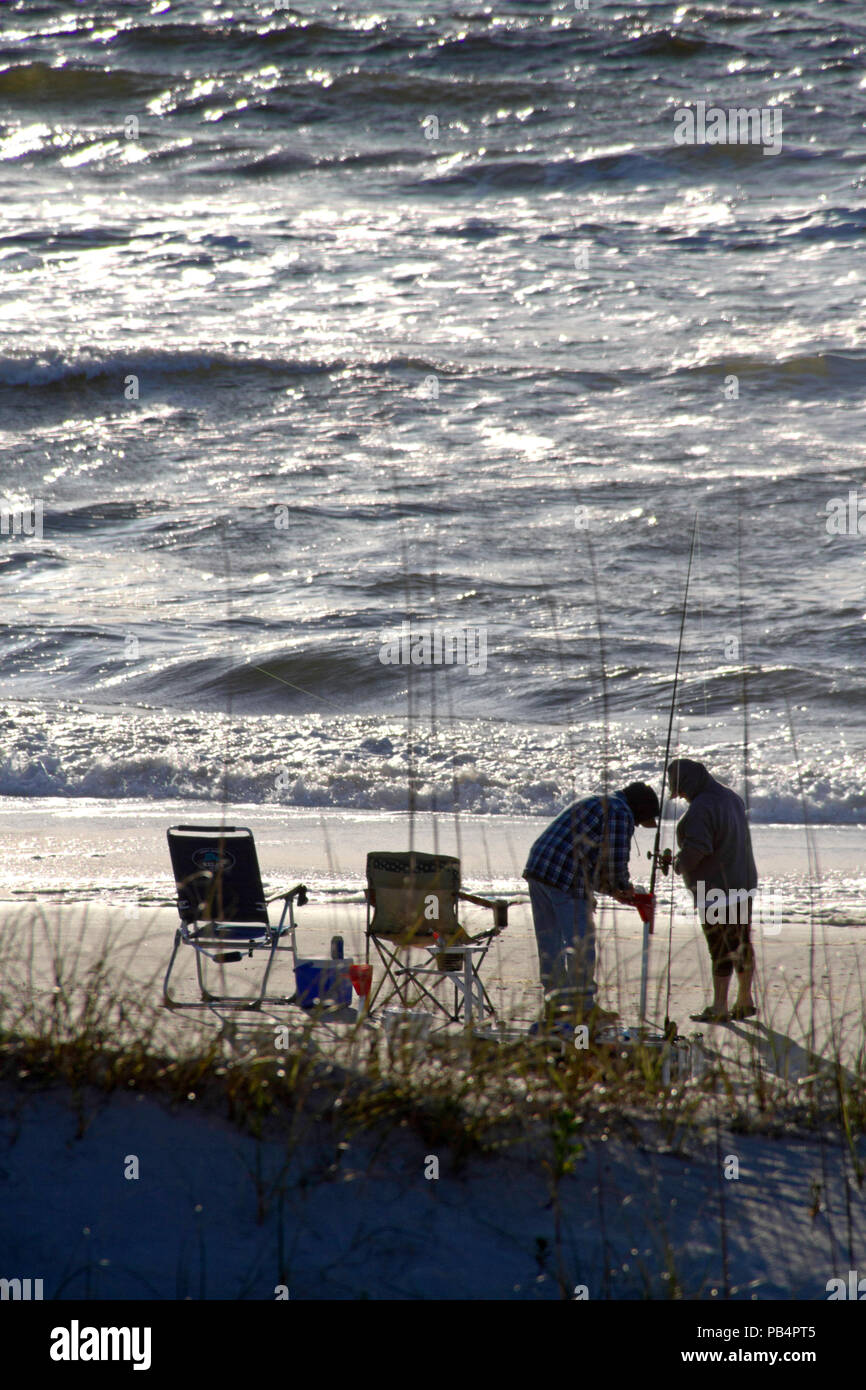 A couple on the beach by a choppy gray sea, with their beach chairs and ...