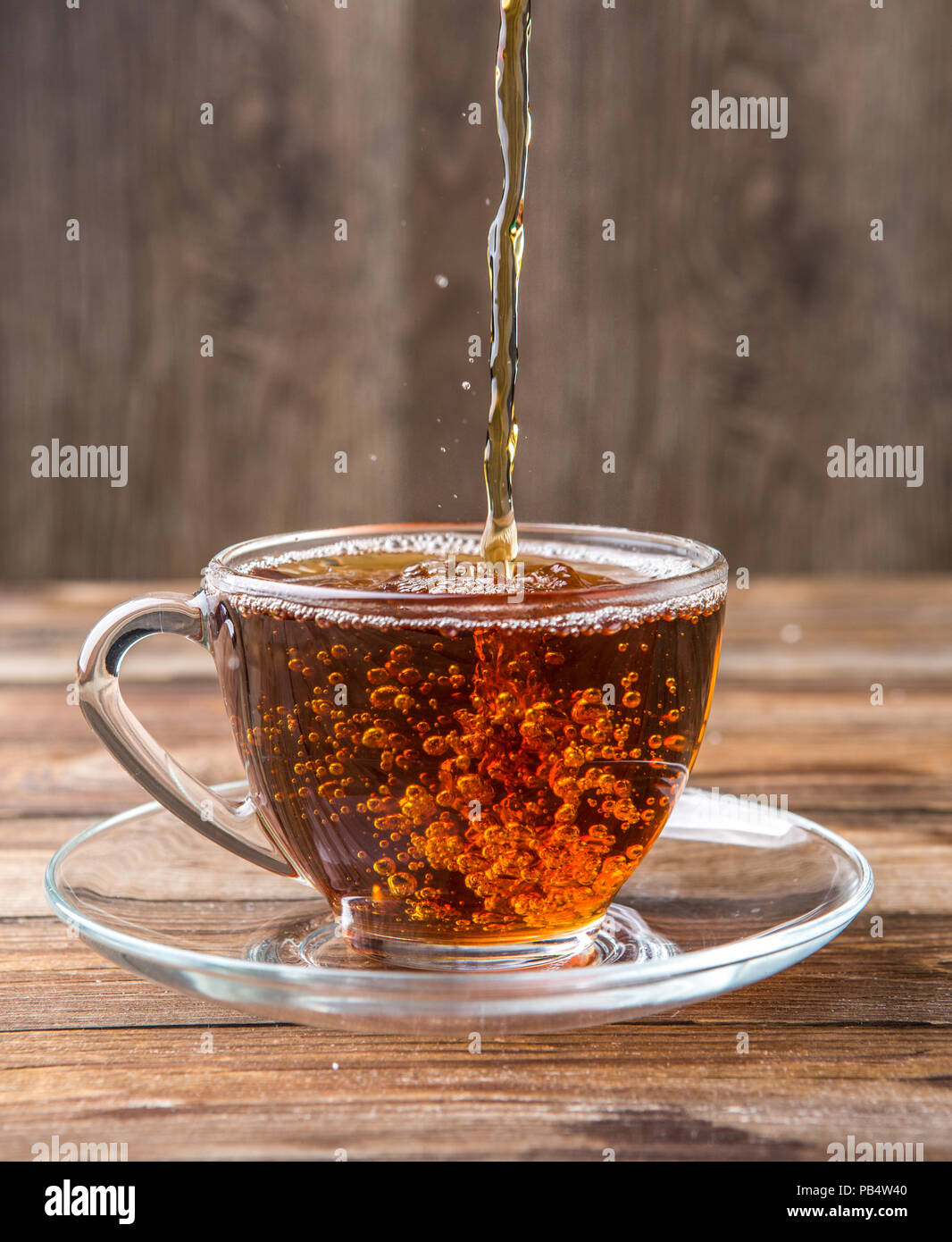 Tea poured into cup , saucer Stock Photo - Alamy
