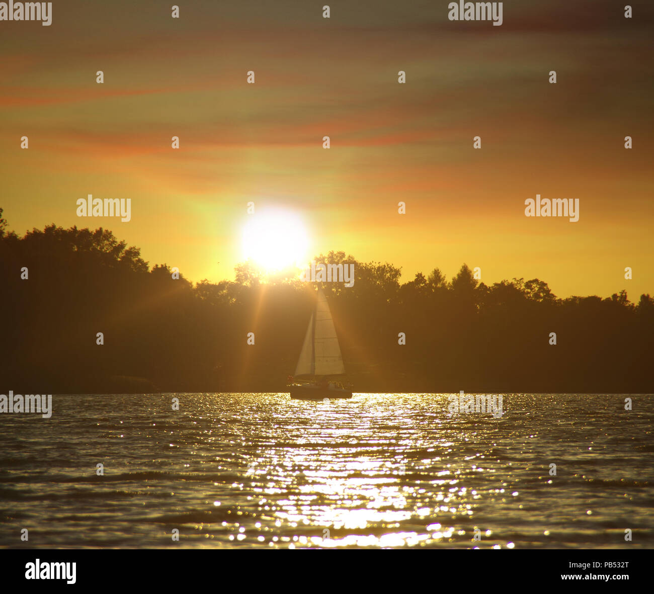 Sailboat on lake on sunset. Dramatic sky and sun in background Stock ...