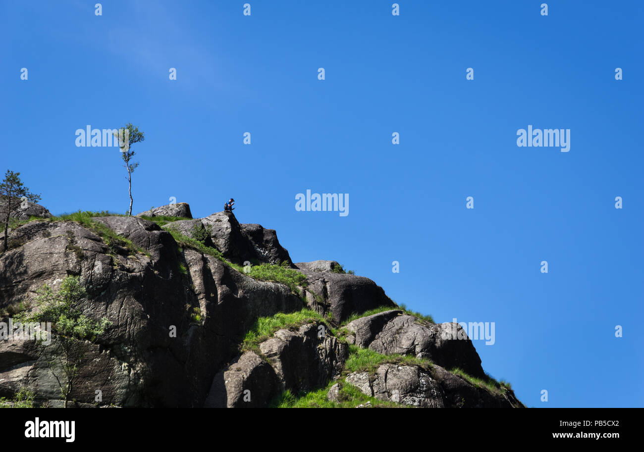 Man Sitting Alone on the Rocks Cliff with Isolated Tree Blue Sky in ...