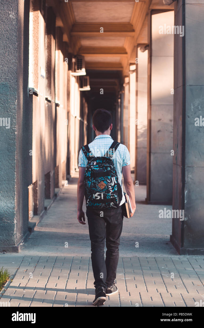 Student holding a notebook and carrying a backpack walking at the front ...