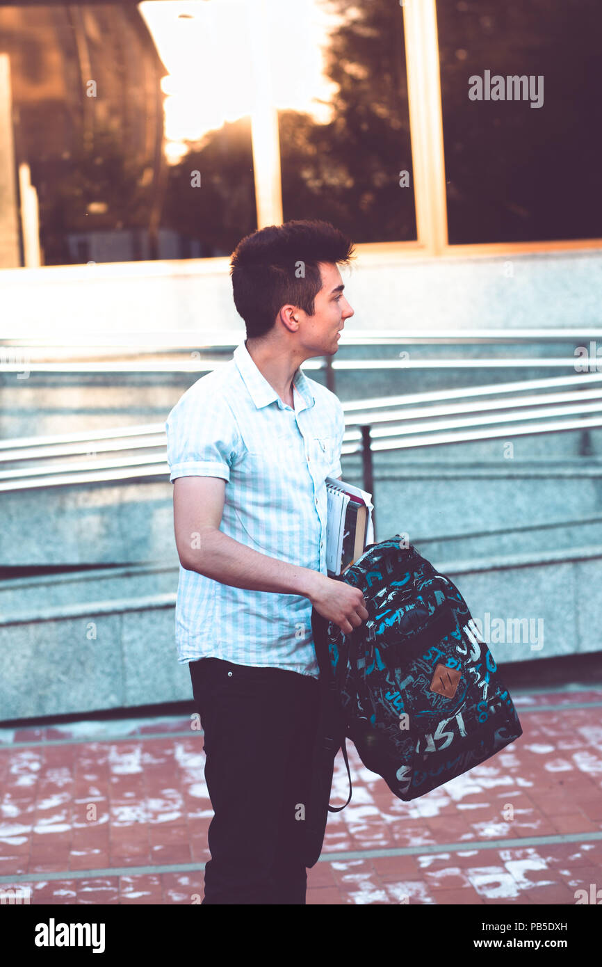 Student putting a notebook to a backpack. Boy standing at front of ...