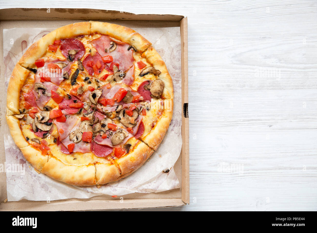 Flat lay of fresh pizza in a cardboard box on white wooden backround ...