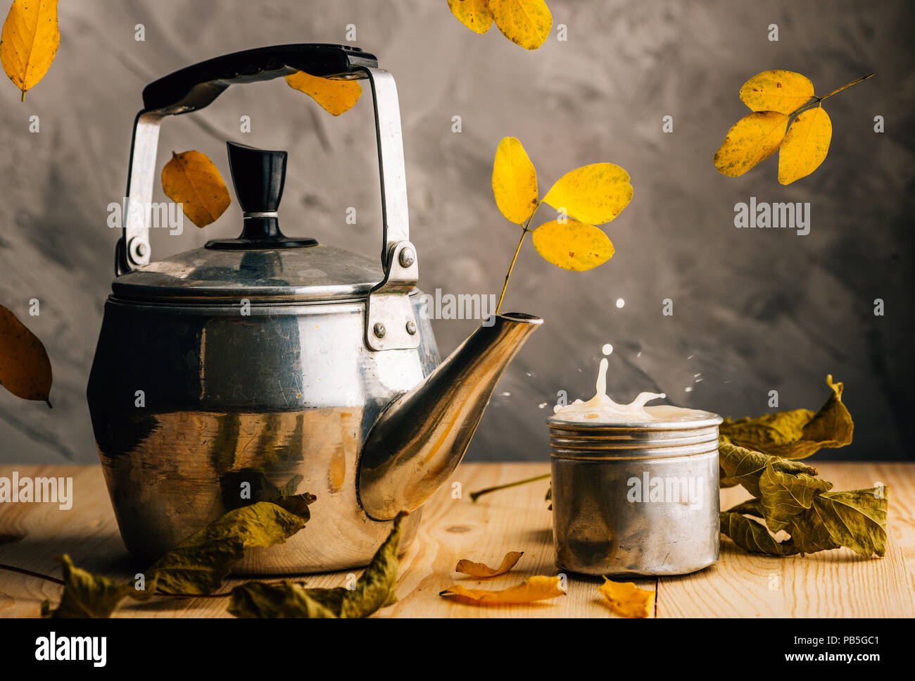 Maple leaves and hot tea in a tea set create an autumn mood. Falling ...