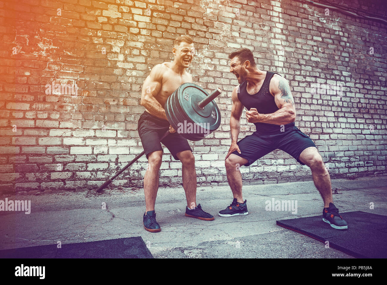 Two muscular athletes training, one raise the bar when other is ...