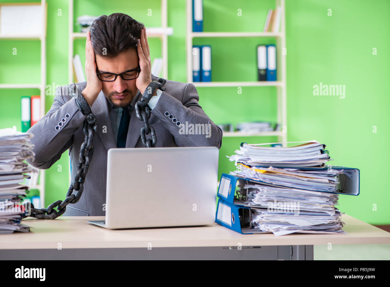 Employee chained to his desk due to workload Stock Photo - Alamy