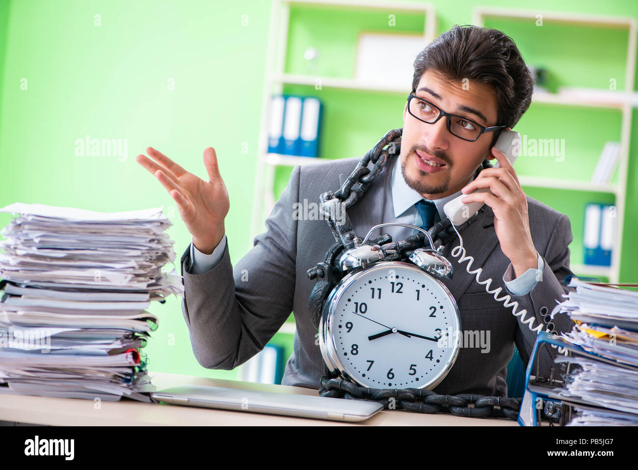 Employee chained to his desk due to workload Stock Photo - Alamy