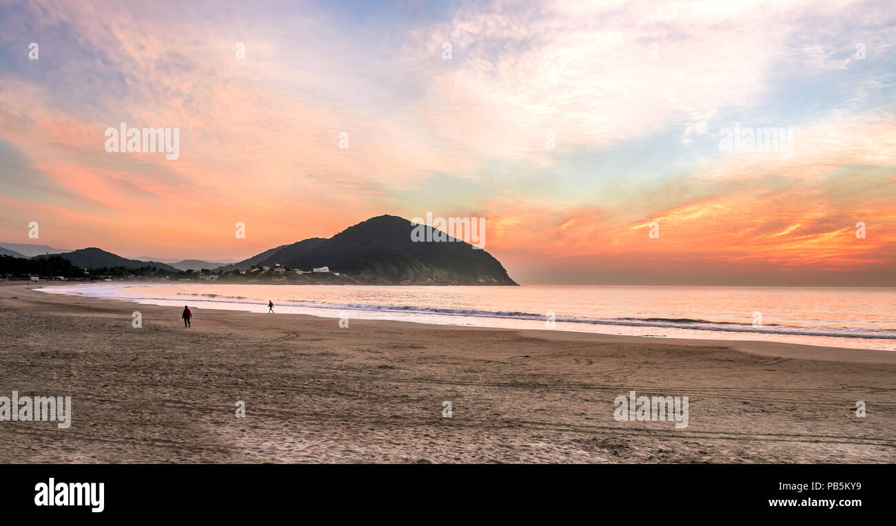 People walking at the beach during sunrise Stock Photo - Alamy