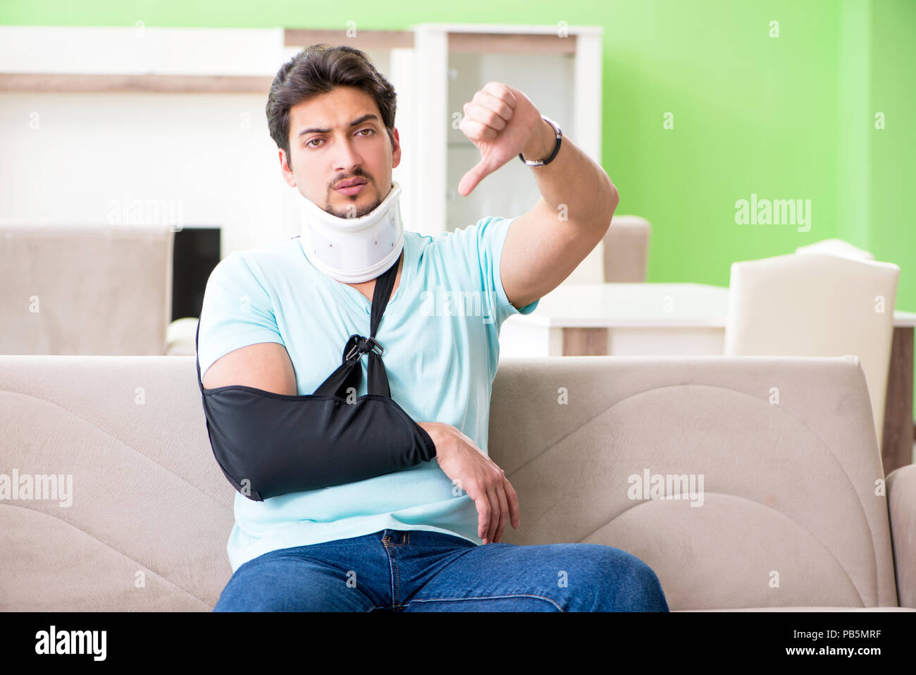 Young student man with neck and hand injury sitting on the sofa Stock ...
