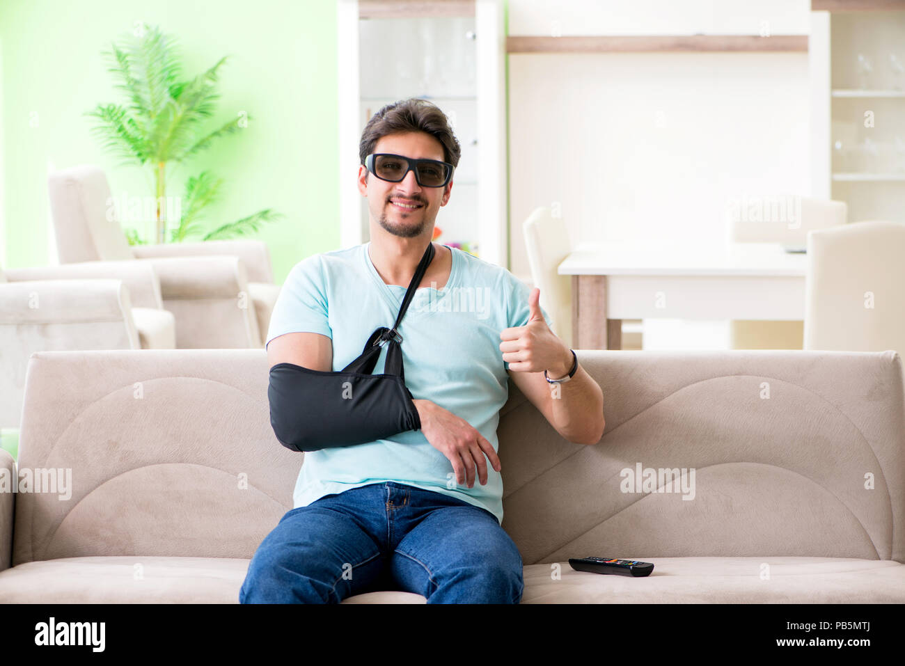 Arm injured man sitting on the sofa watching tv Stock Photo - Alamy