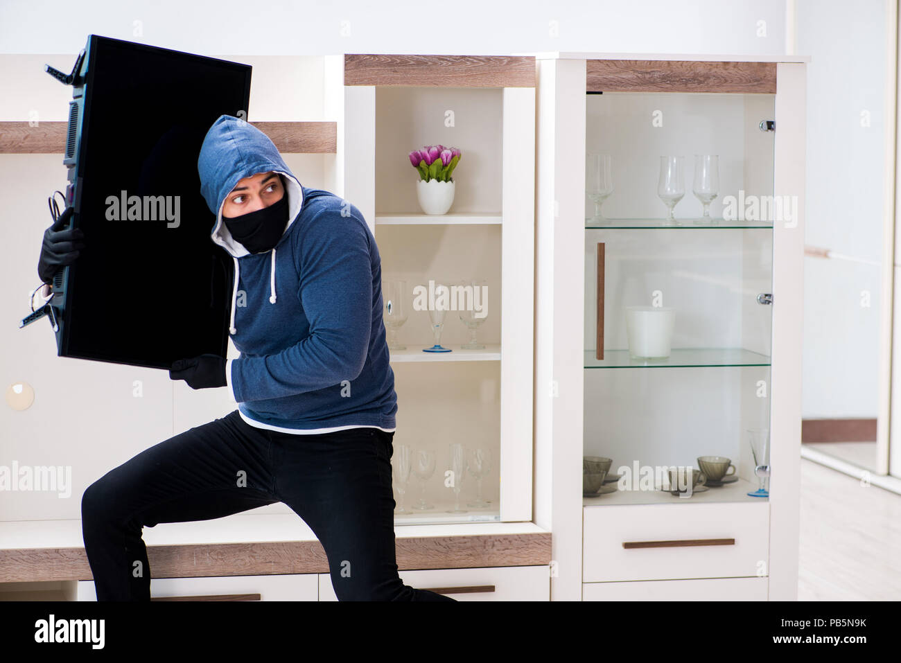 Man burglar stealing tv set from house Stock Photo - Alamy
