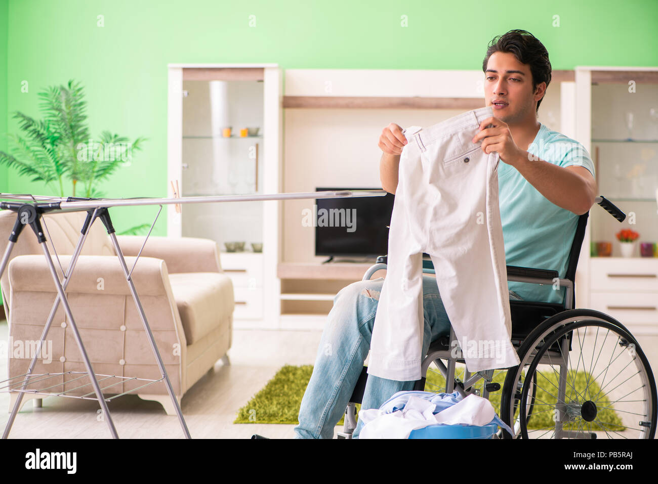 Disabled man on wheelchair doing laundry Stock Photo - Alamy