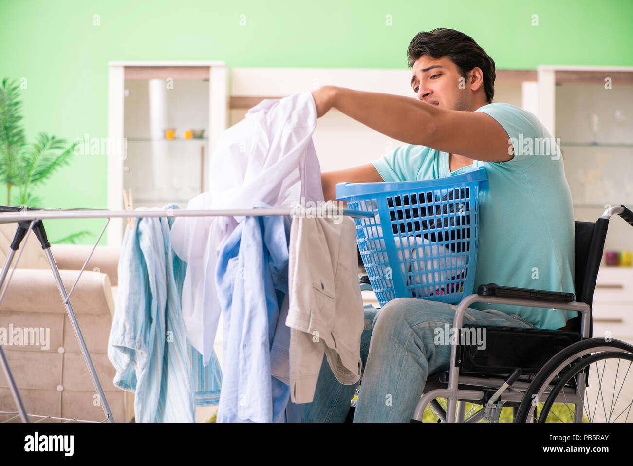 Disabled man on wheelchair doing laundry Stock Photo - Alamy
