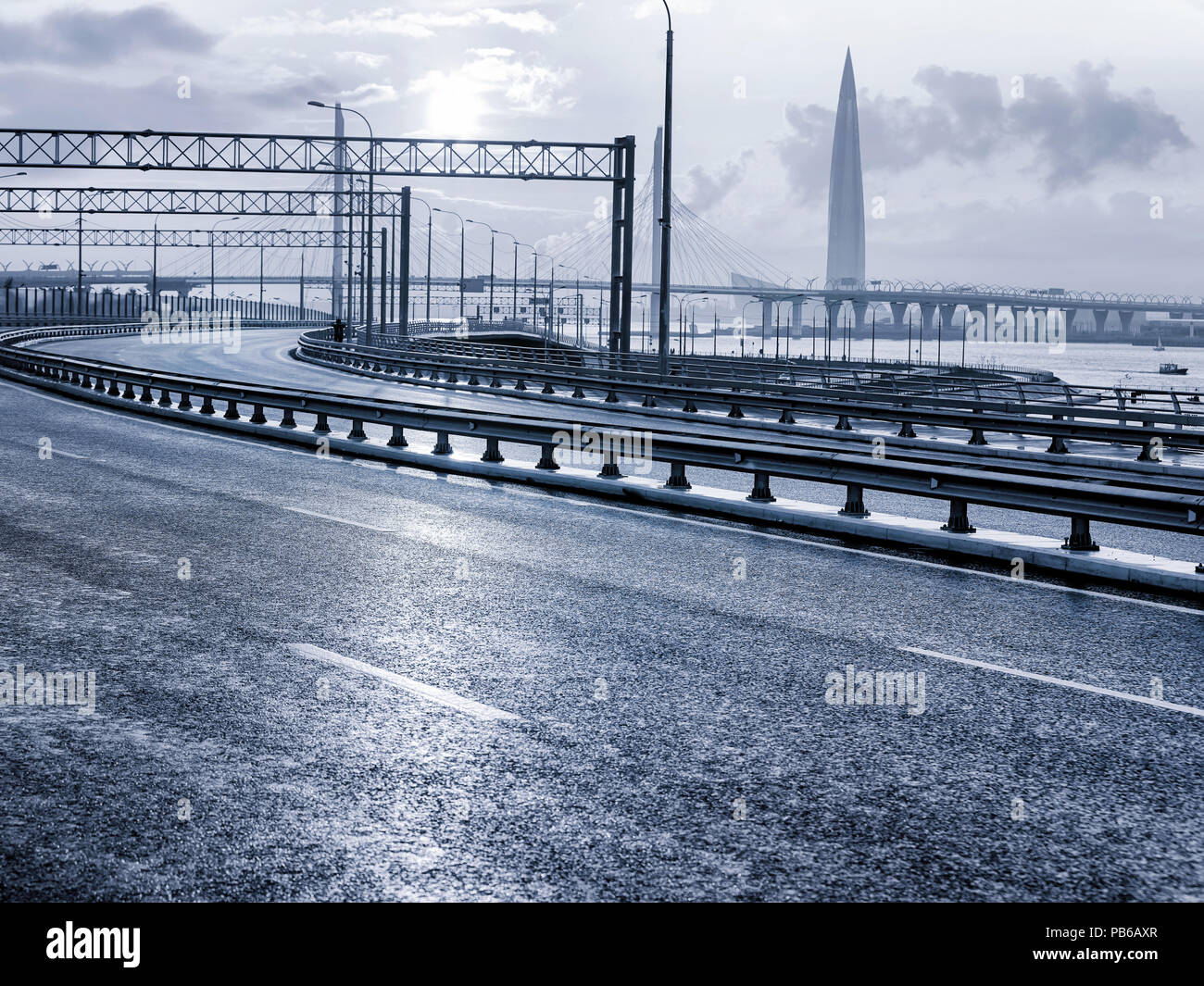 Cityscape at sunset. Empty highway and distant bridge. Toned black and ...