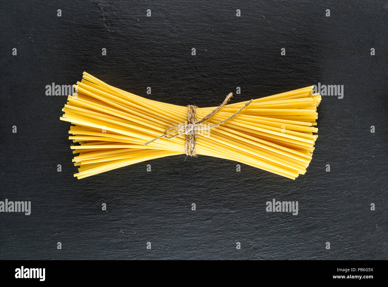 raw spaghetti tied with a rope on a black background, top view Stock ...