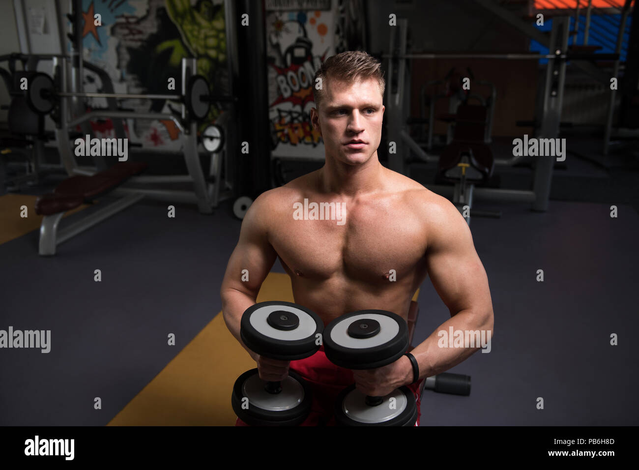 Strong Man In The Gym And Exercising Chest With Dumbbells - Muscular ...