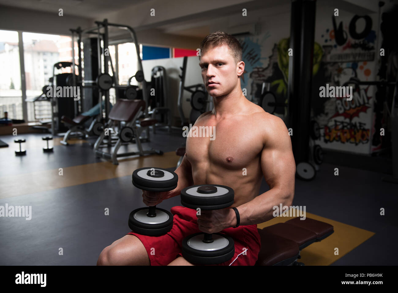 Strong Man In The Gym And Exercising Chest With Dumbbells - Muscular ...