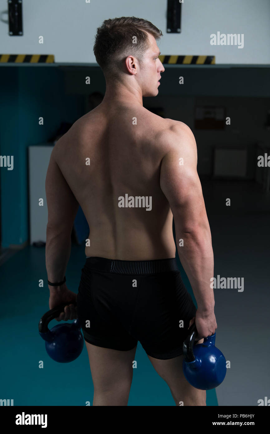 Young Man Exercising With Kettle Bell And Flexing Muscles - Muscular ...