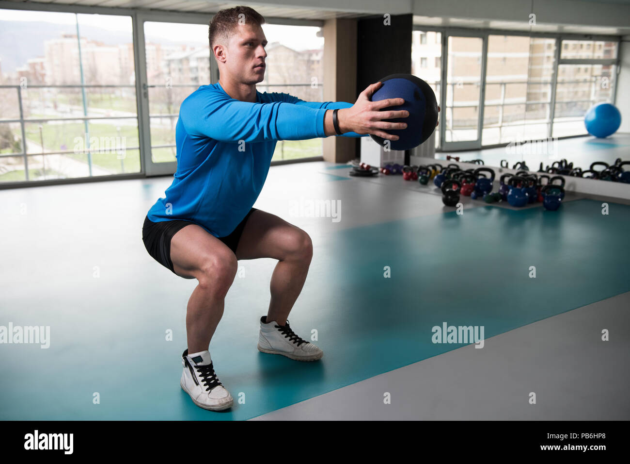 Handsome Young Man Doing Squad With Medicine Ball As Part Of