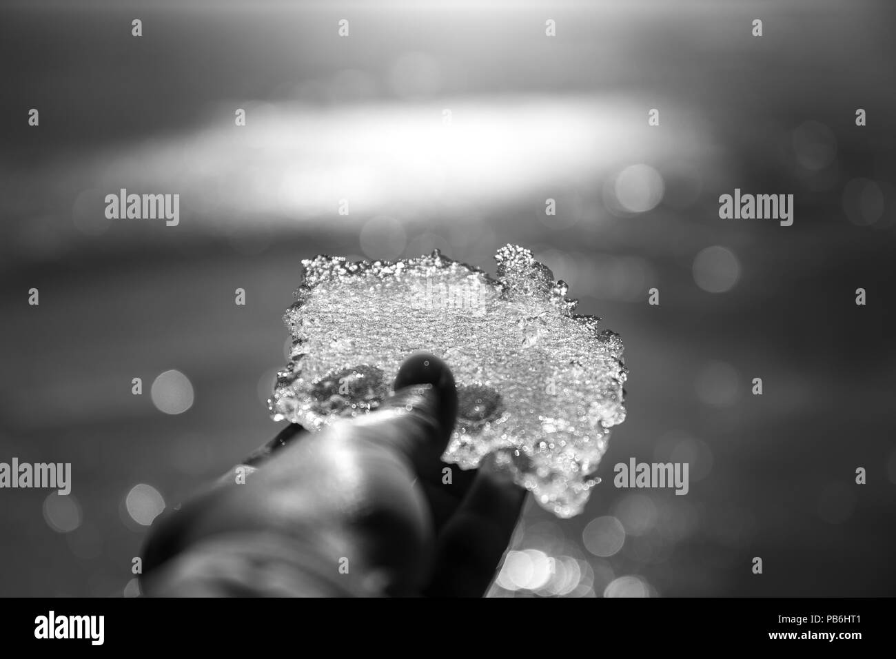 Hand holding a piece of broken ice up in the sun Stock Photo - Alamy