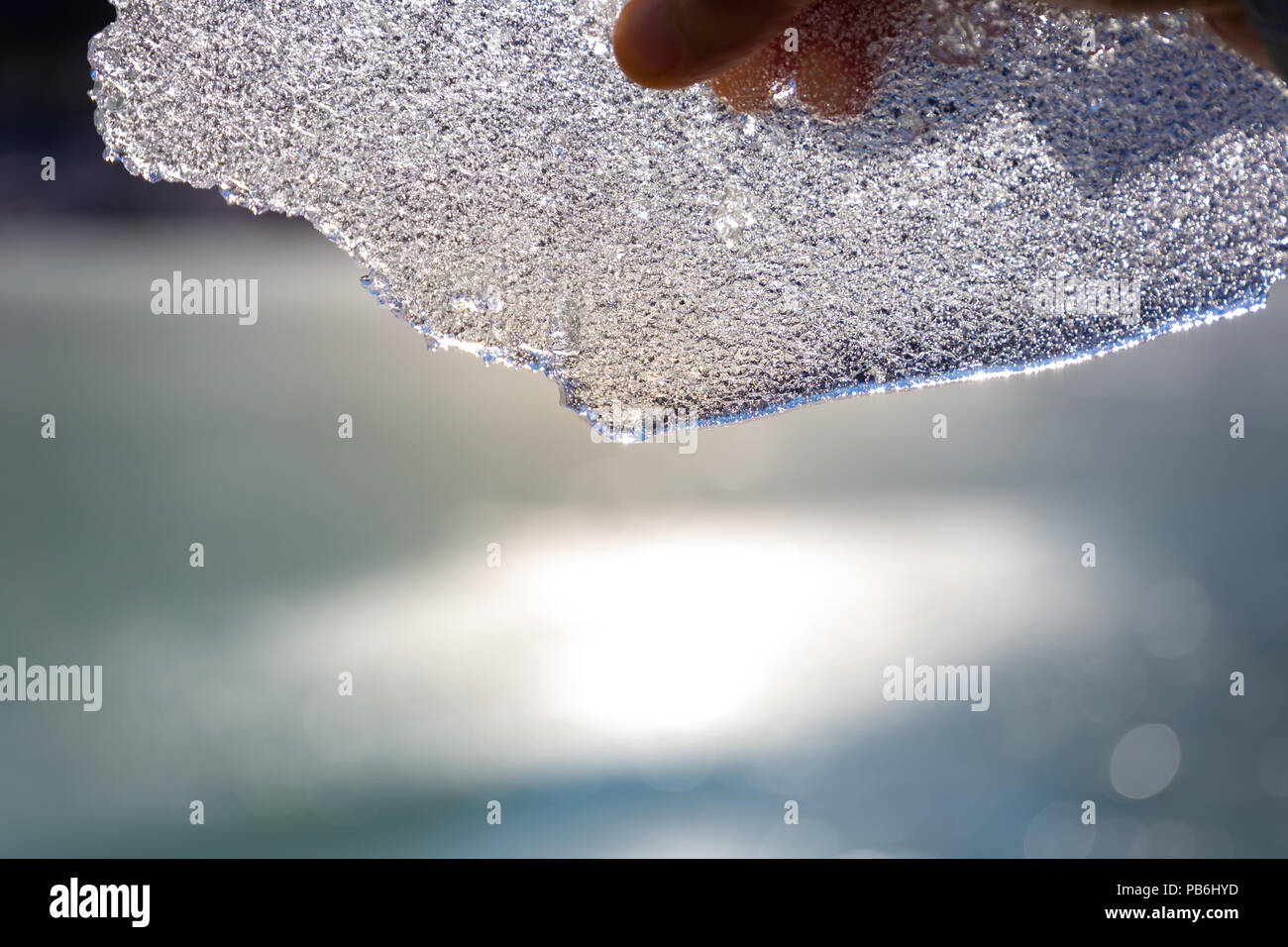 Hand holding a piece of broken ice up in the sun Stock Photo - Alamy