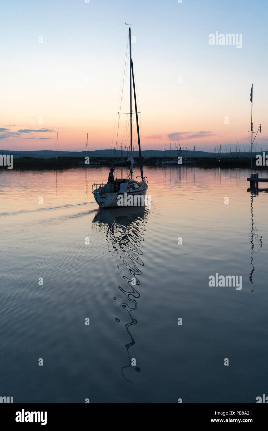 A sailing boat sailing off into the sunset on a summer's night and ...