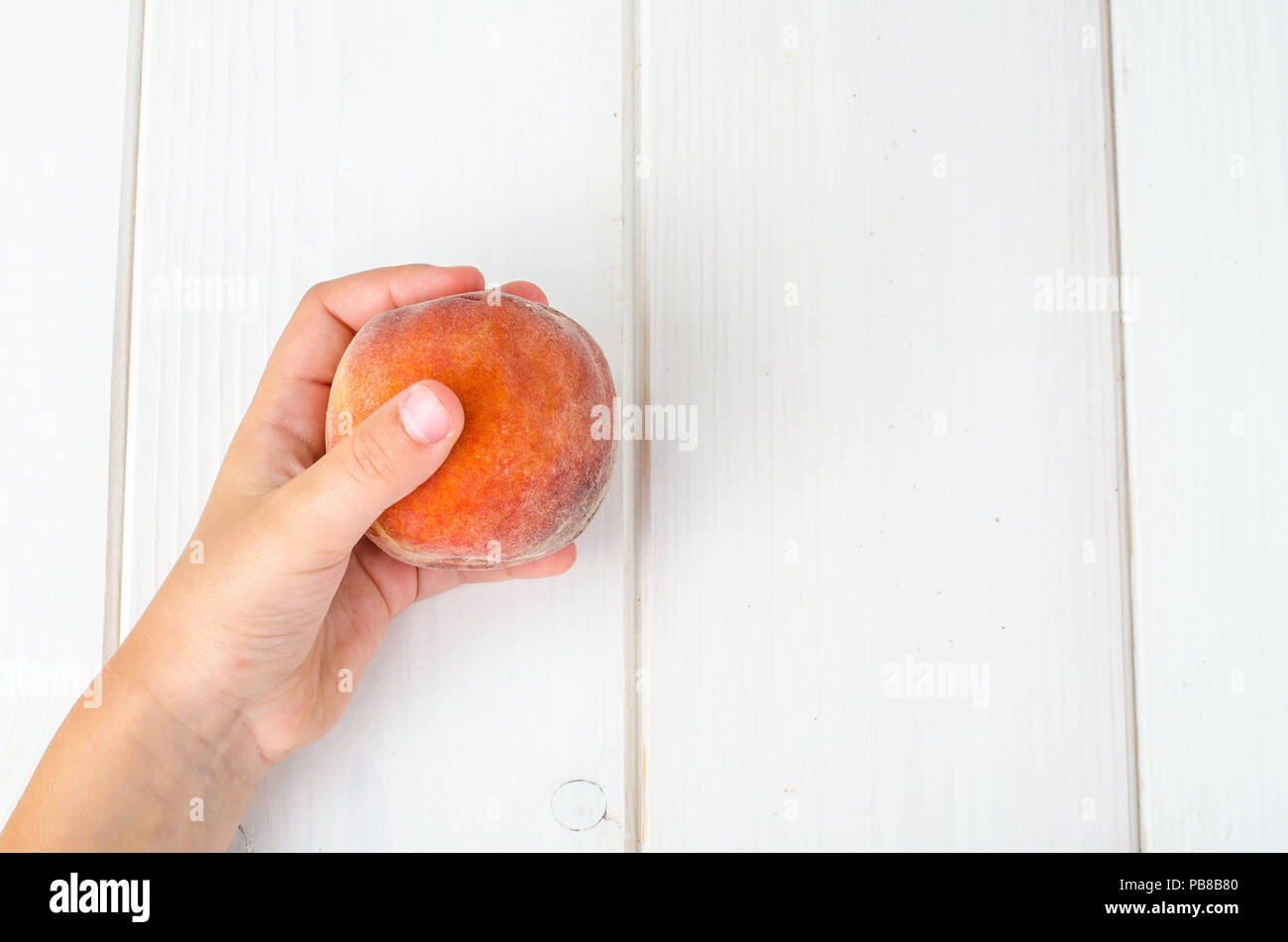 Child's hand holds peach. Studio Photo Stock Photo - Alamy