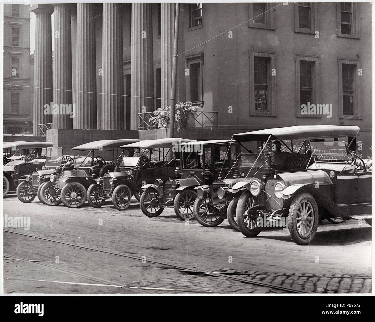 1273 Row of cars parked in front of an unidentified building with large ...