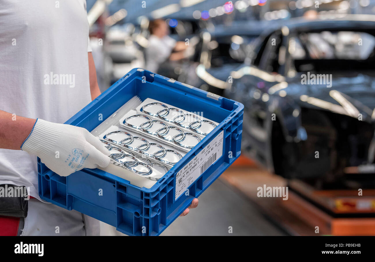 An Audi employee holds a box of Audi logos on the Audi A4 assembly line ...