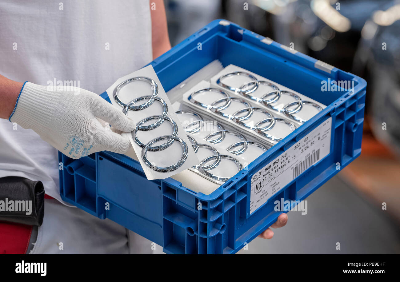 An Audi employee holds a box of Audi logos on the Audi A4 assembly line ...