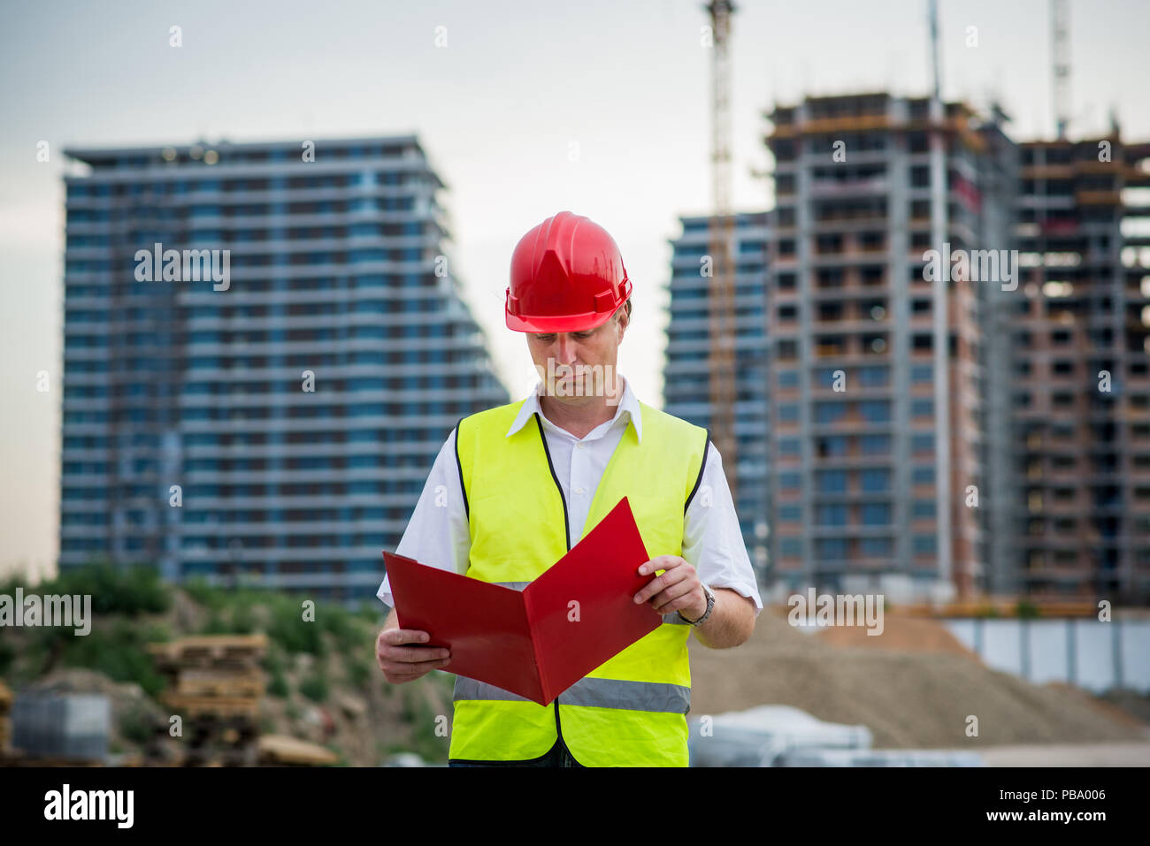 Architect on a construction site looking at project documents ...