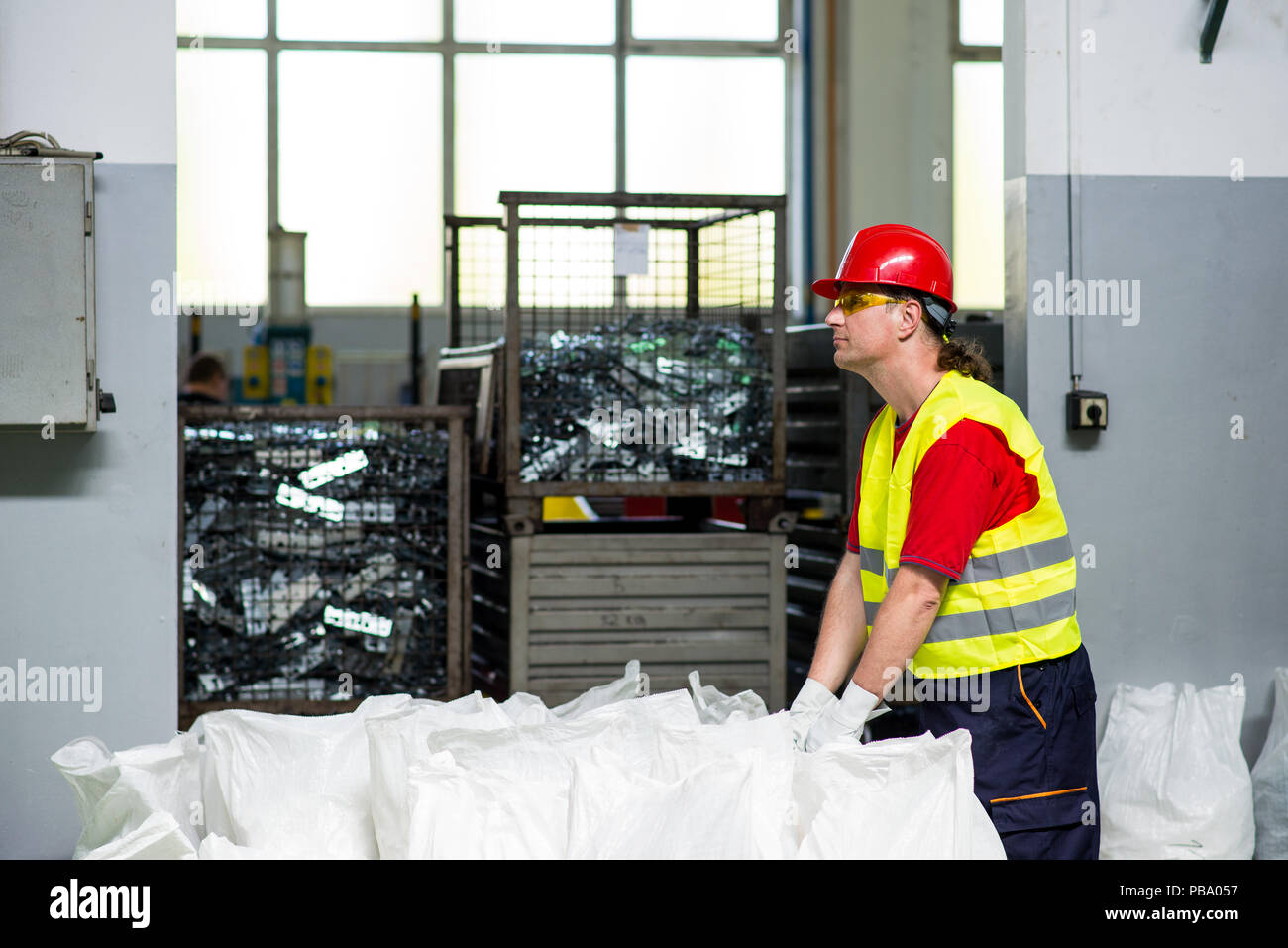 Factory worker standing beside loaded sacks Stock Photo - Alamy