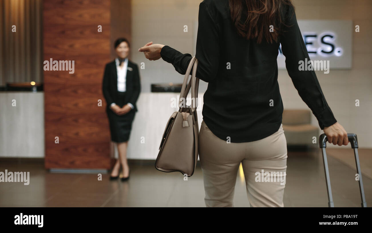 Rear view of business woman arriving at hotel with luggage. Female ...