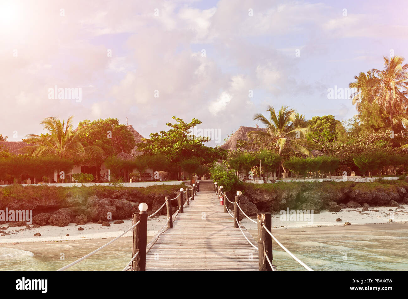 wooden bridge over the beach that leads to the palm trees Stock Photo ...