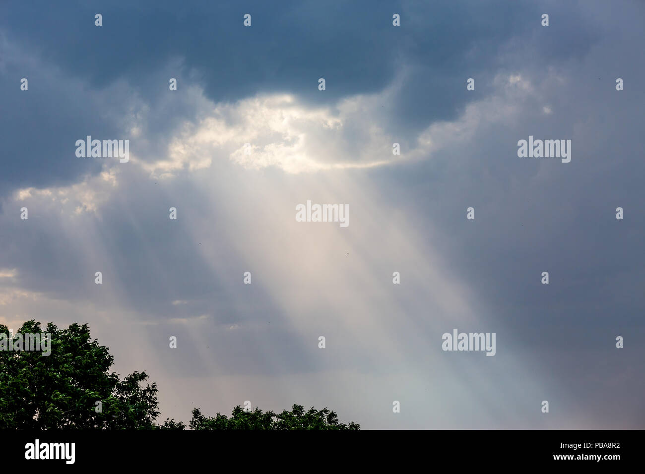 Rays of lights coming through dark clouds just before heavy rain ...