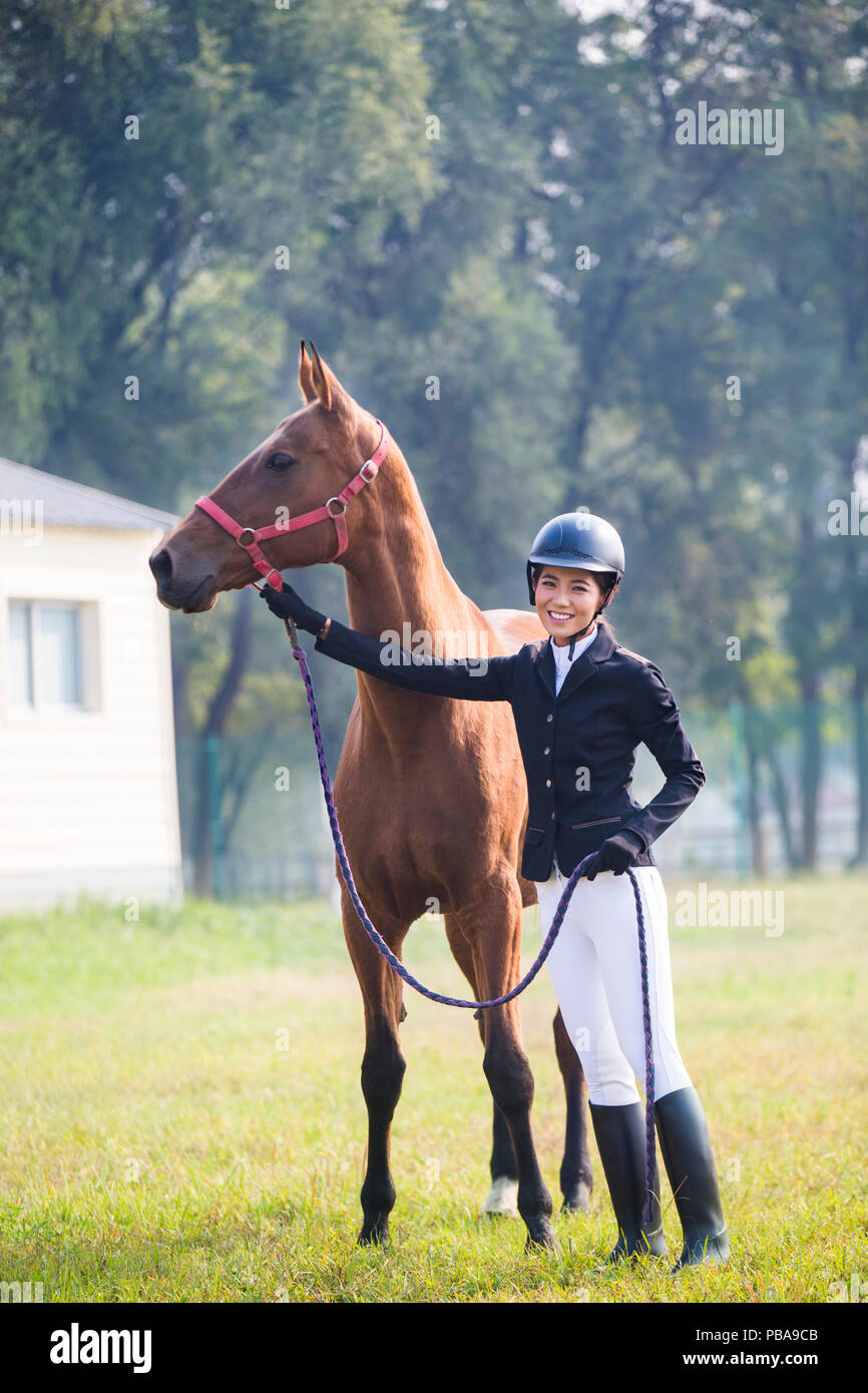 Cheerful Chinese female rider with her horse Stock Photo - Alamy