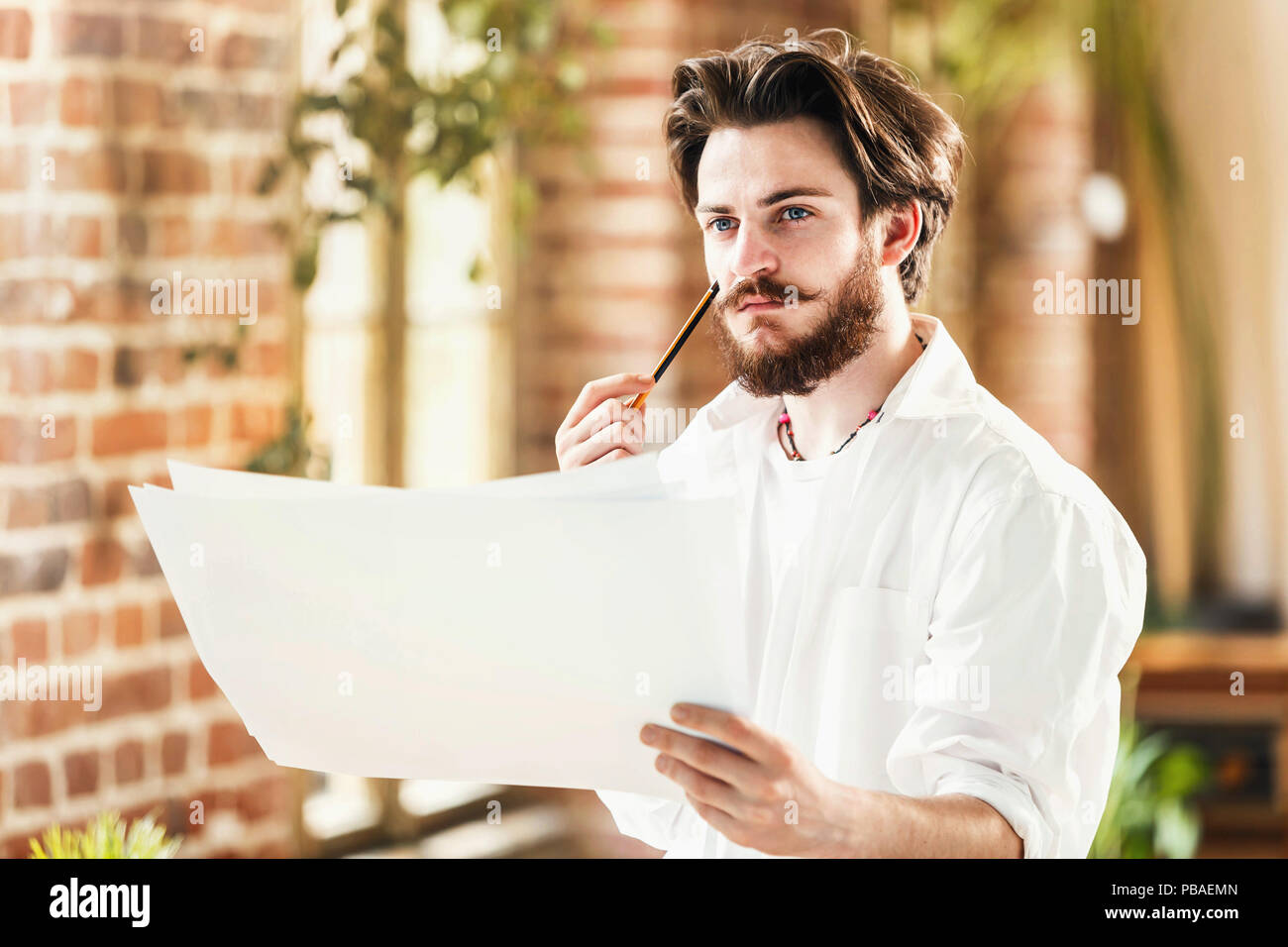 Bearded male architect in white shirt thinking and analyzing the ...