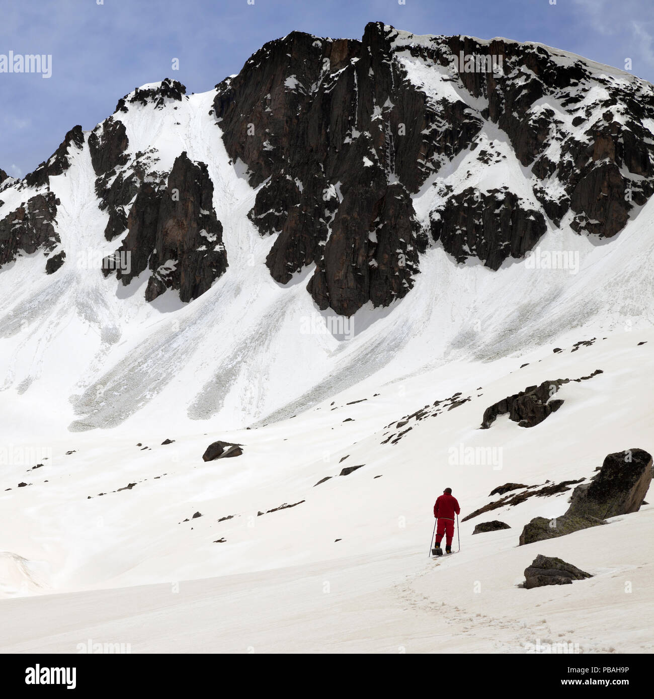 Hiker in snowy mountain with trace from avalanches at sun spring day ...