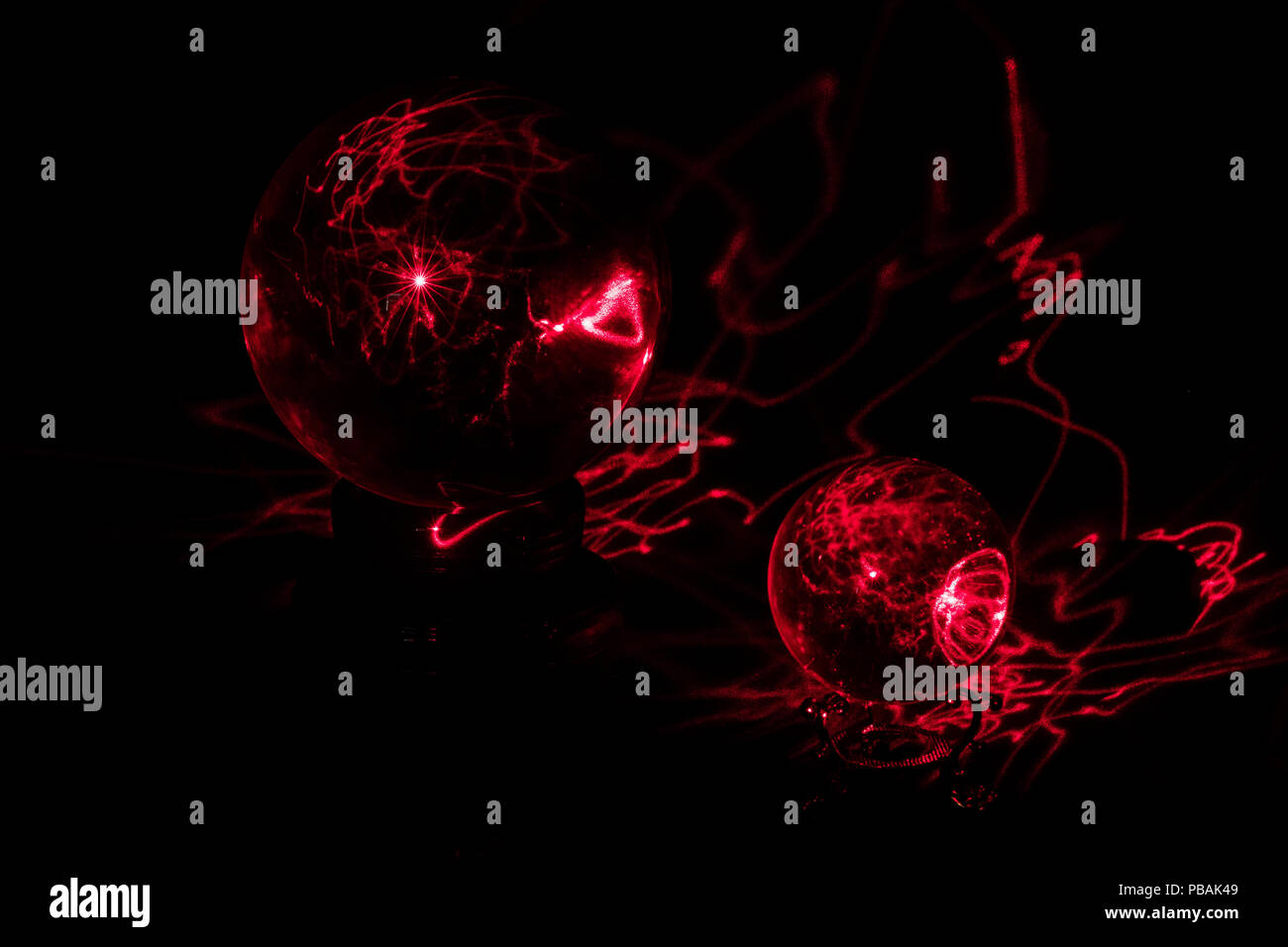 A red laser beam is directed at a large and a small crystall ball, with ...