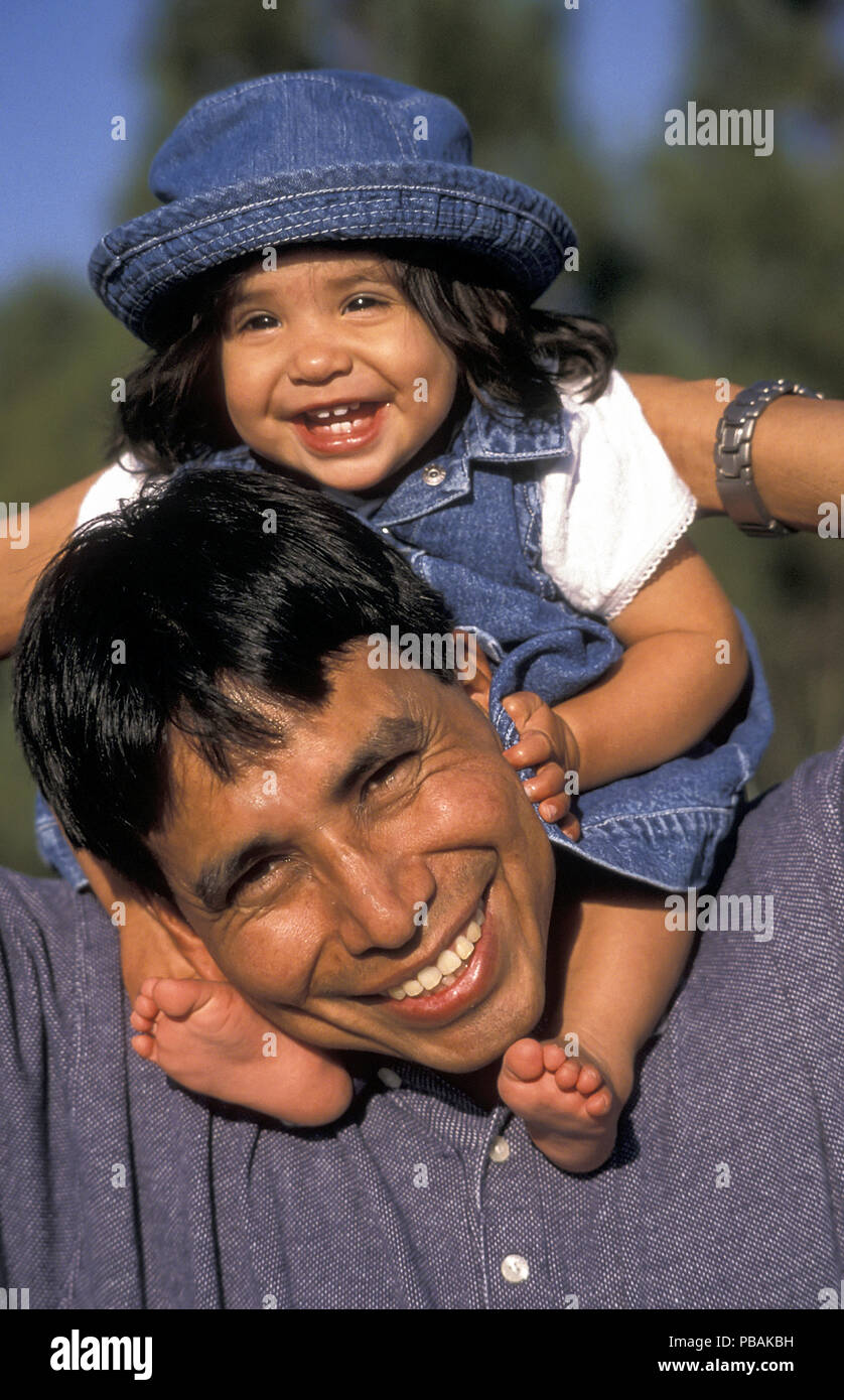 Toddler infant daughter sitting on the shoulders of Native American dad ...