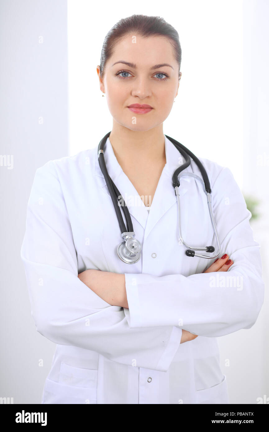 Brunette female doctor standing straight at hospital. Medicine and ...