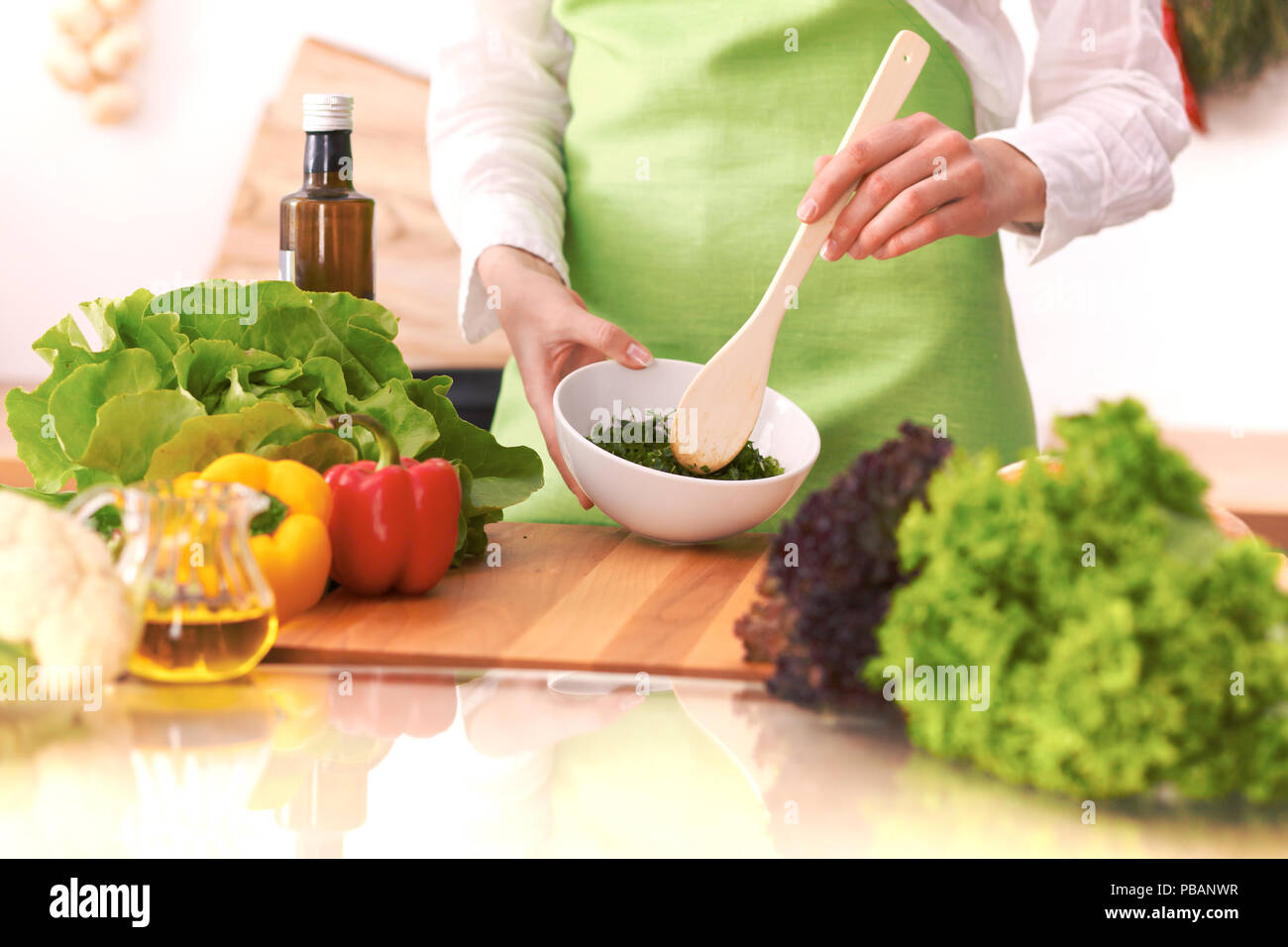 Close Up of human hands cooking vegetable salad in kitchen on the glass ...